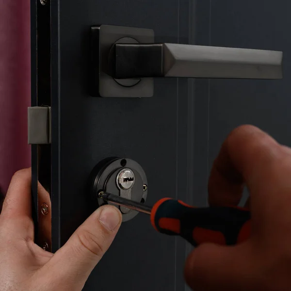 Installation of a door lock, a carpenter installs a door lock in a door ...