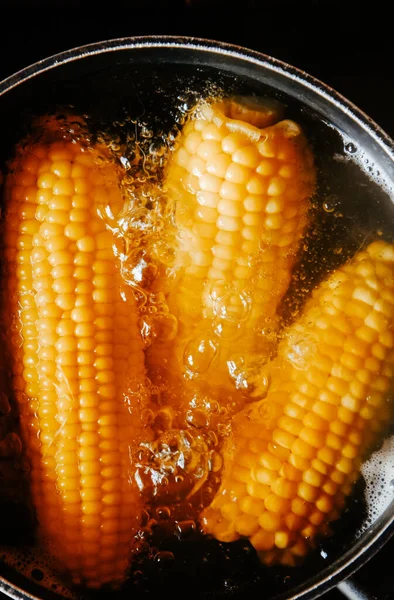 Orange juicy corn is boiled in water with salt. Corn in boiling water ...