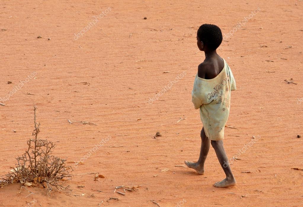 Poor boy walking barefoot on the sandl. Poverty concept — Stock Photo ...