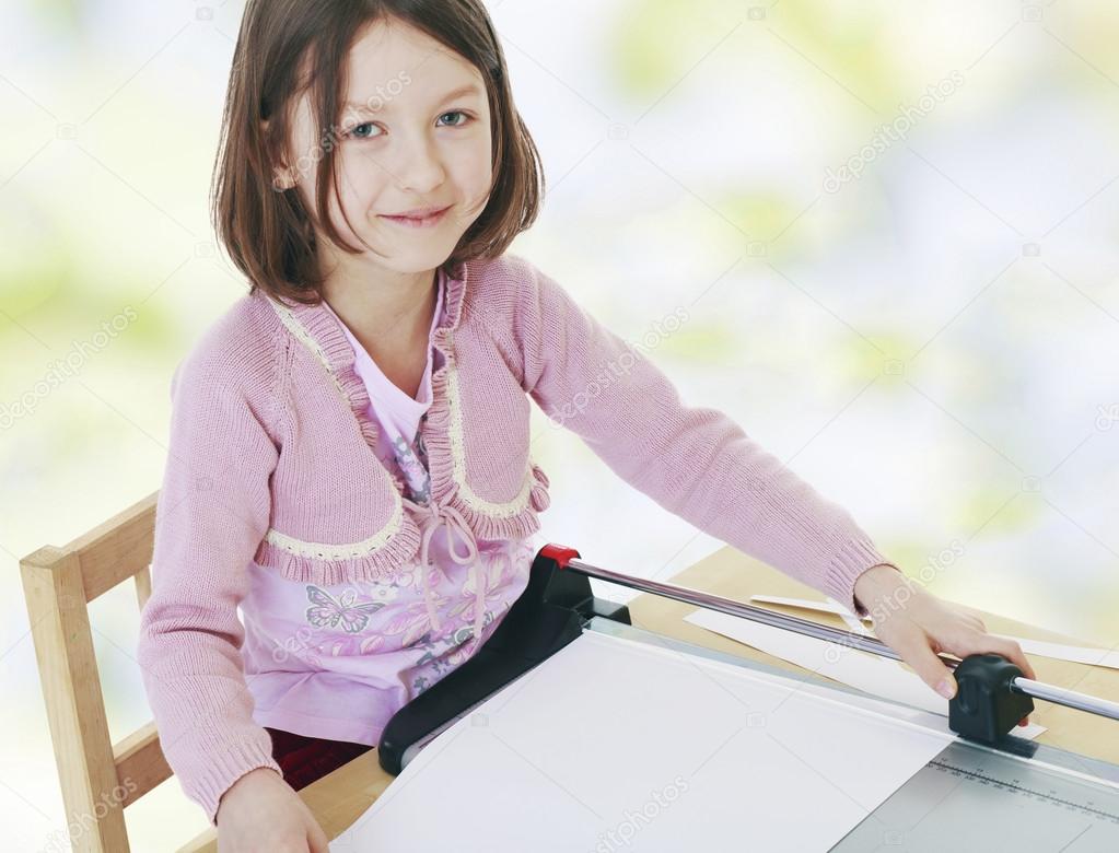Girl cutting paper roller cutter. Stock Photo by ©lotosfoto1 49155929
