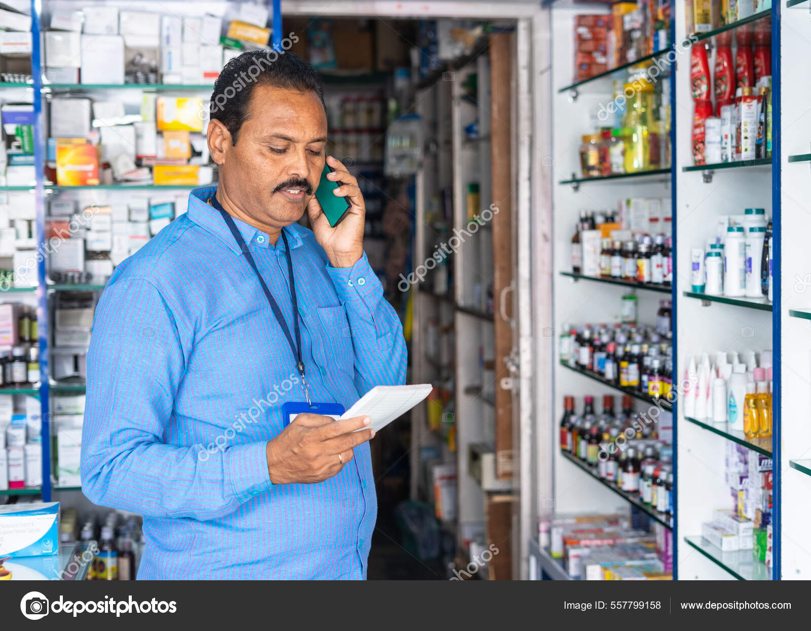 Pharmacist talking on mobile phone with customer about prescription ...