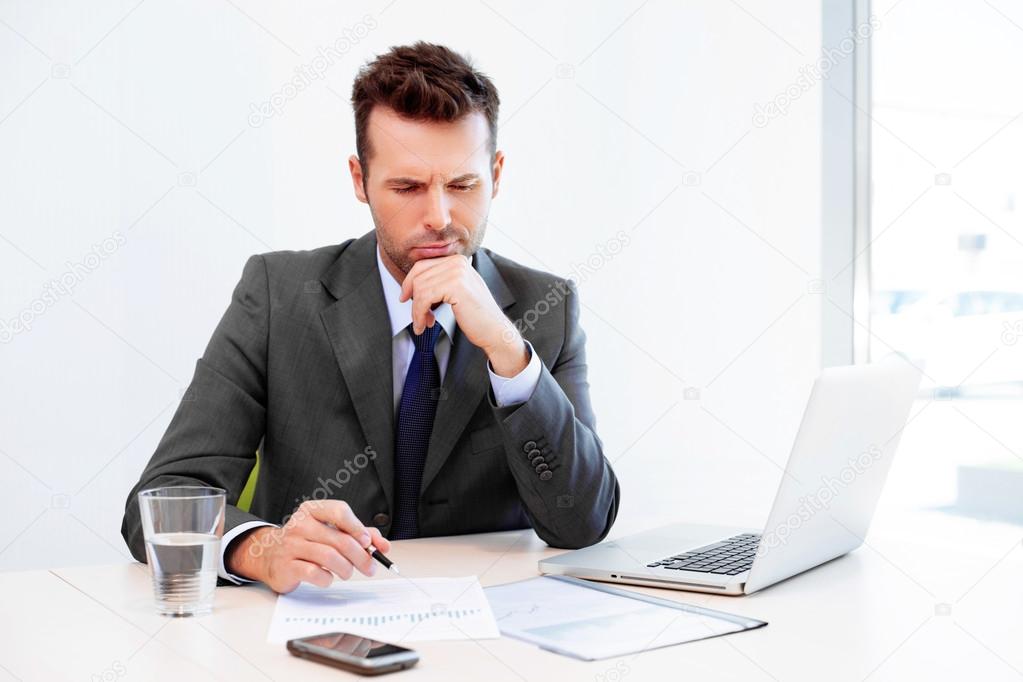 Thoughtful man analyzing documents Stock Photo by ©baranq 36191621