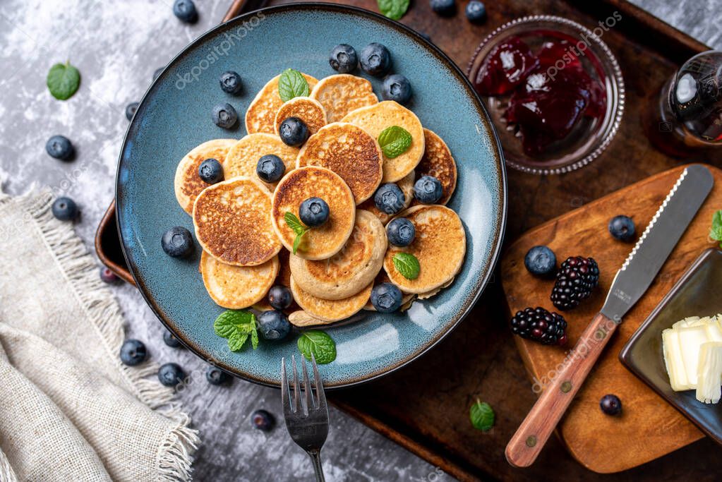 Mini panqueques en un plato con arándanos, jalea y mantequilla ...