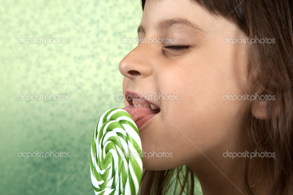 Girl enjoy licking a lollipop. Stock Photo by ©vkarafill 47471879