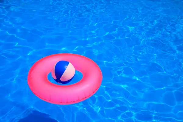 Colorful inflatable ball and round tube floating in swimming pool ...
