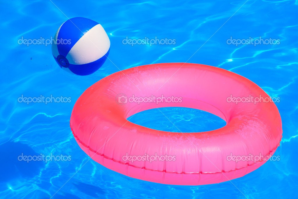 Colorful inflatable ball and round tube floating in swimming pool ...