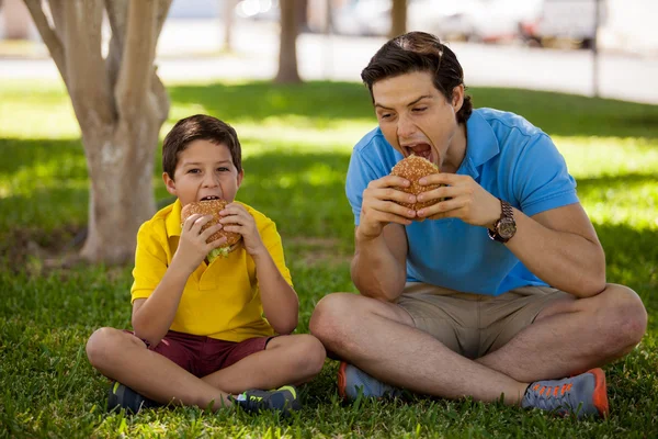 Dad and son eating lunch in the park on sunny day Stock Photo by ...