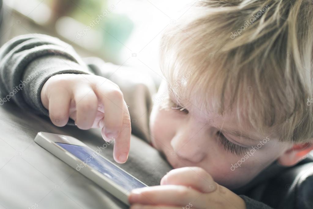 Boy playing on smartphone Stock Photo by ©Mactrunk 40348333
