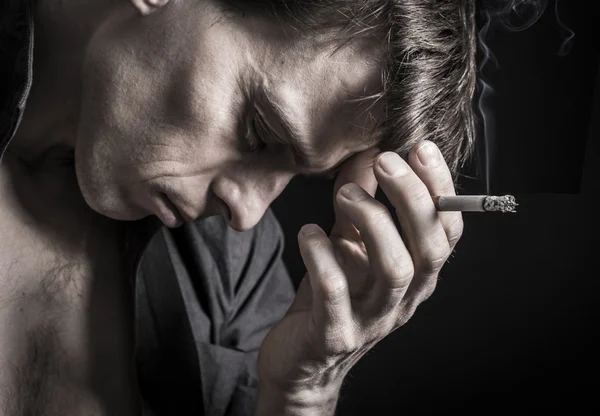 Depressed man smoking cigarette Stock Photo by ©Mactrunk 40612597