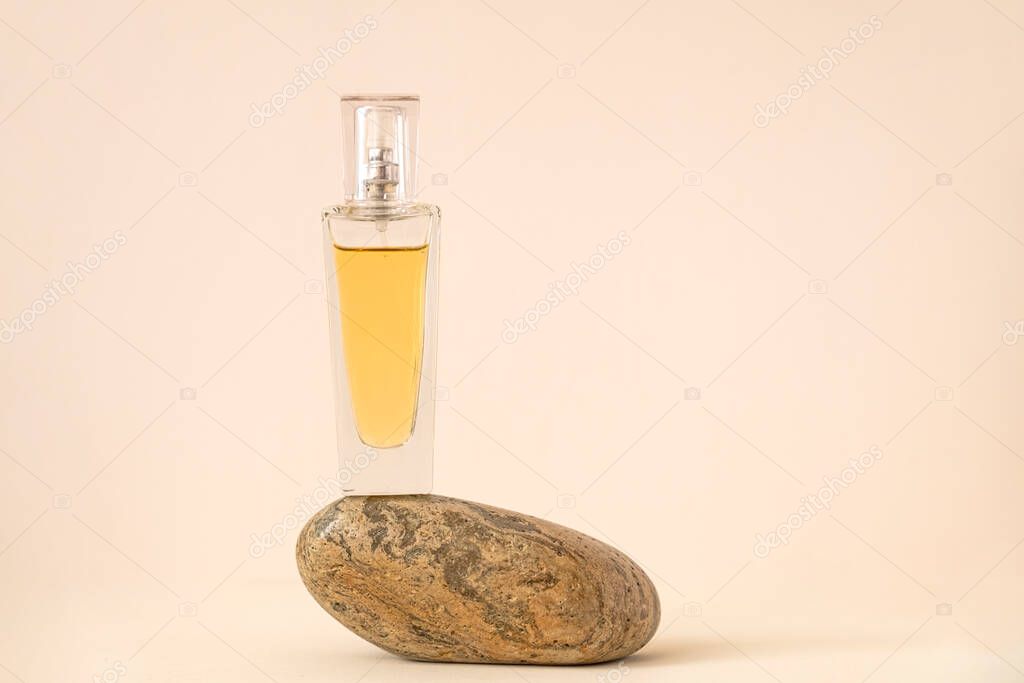 Frasco de perfume amarillo balanceándose sobre la piedra de color beige ...