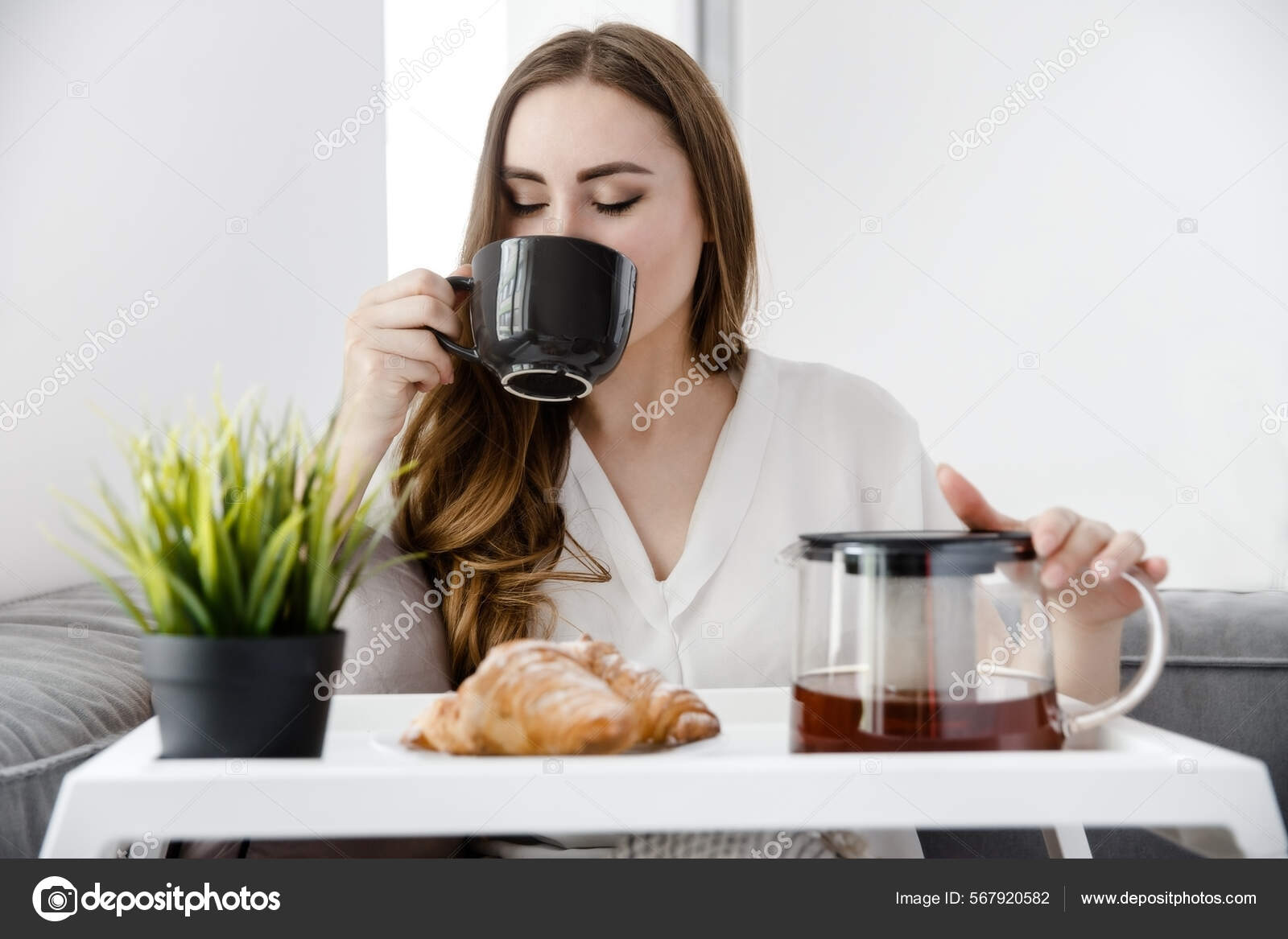 A Young Girl take Breakfast in Bed. French Croissants With Tea on a ...