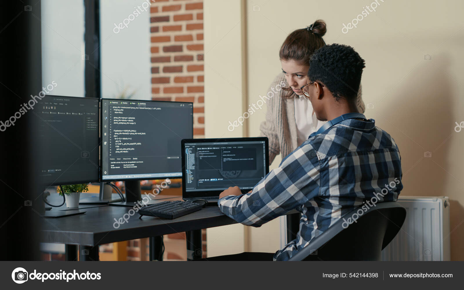 Two programmers doing high five hand gesture at desk with multiple screens running code ...
