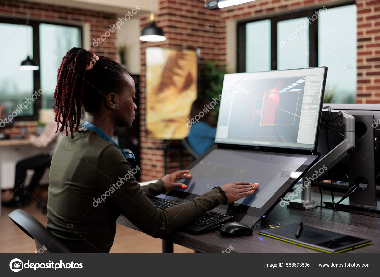 3D digital artist sitting at computer desk while working on ...