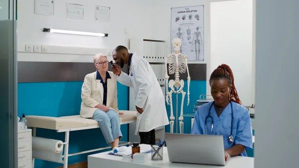 Otologist doing ear examination with otoscope on old patient, using ...