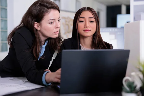 Architects working with cad software on laptop, discussing ...