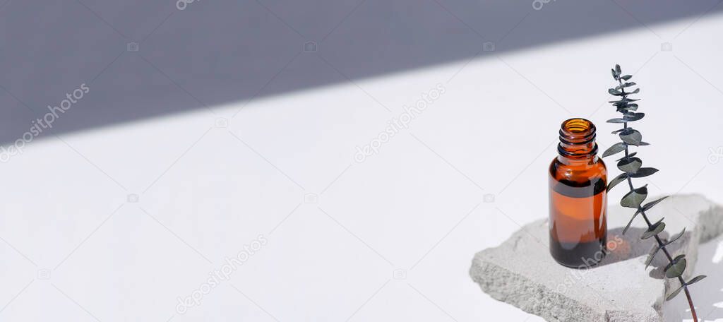 Frasco ámbar abierto sin tapa con rama de eucalipto. Fondo blanco con ...