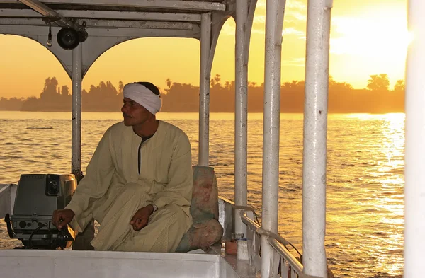 Egyptian captain driving his boat on the Nile river at sunset, L ...