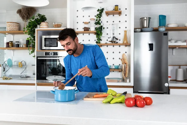 Young man cancer survivor cooking and preparing vegetarian meal after ...