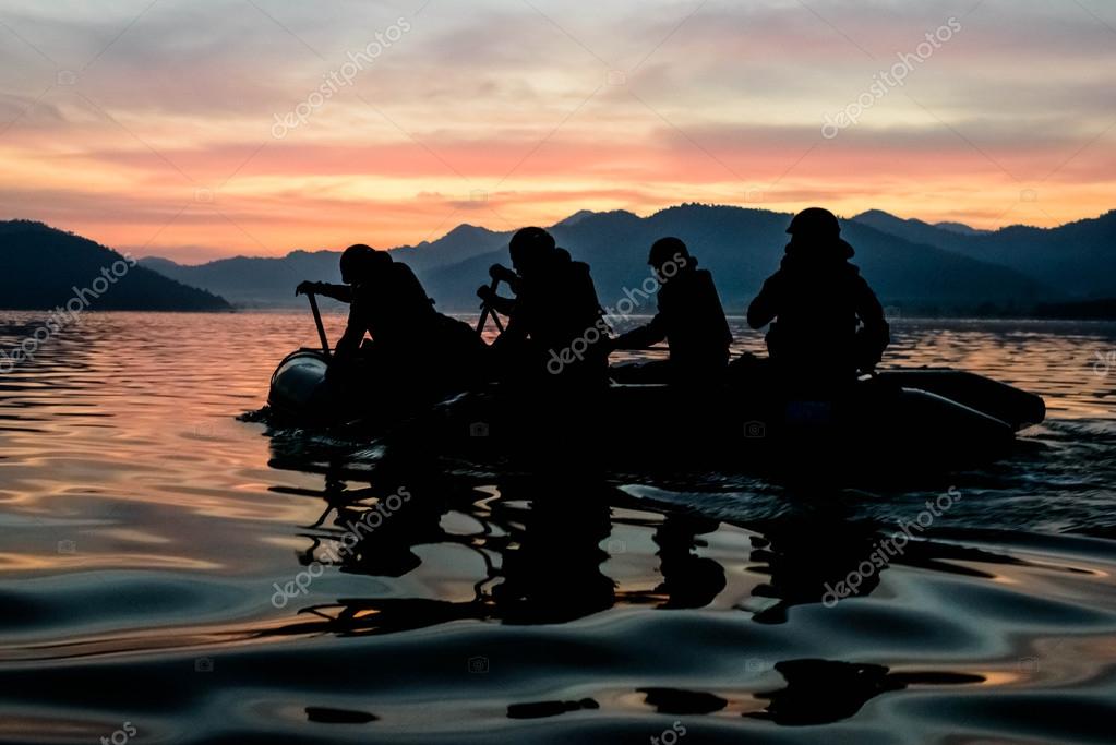 Silueta de soldados remando bote de goma en el lago 2022