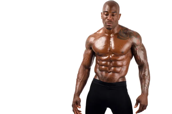 Black bodybuilder pouring oil on his muscles. Strong man with perfect ...