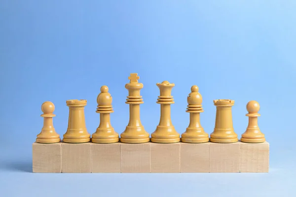 White chess pieces on wooden blocks with blue background. Concept of ...