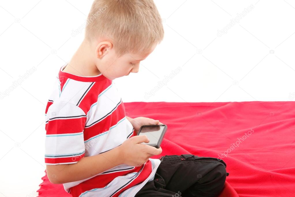 Child plays games on the mobile phone Stock Photo by ©Voyagerix 24552885