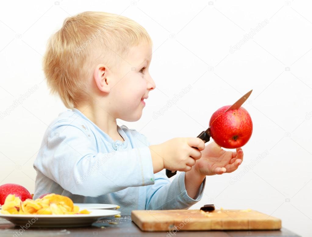 Blond boy child kid preschooler with kitchen knife cutting fruit apple ...