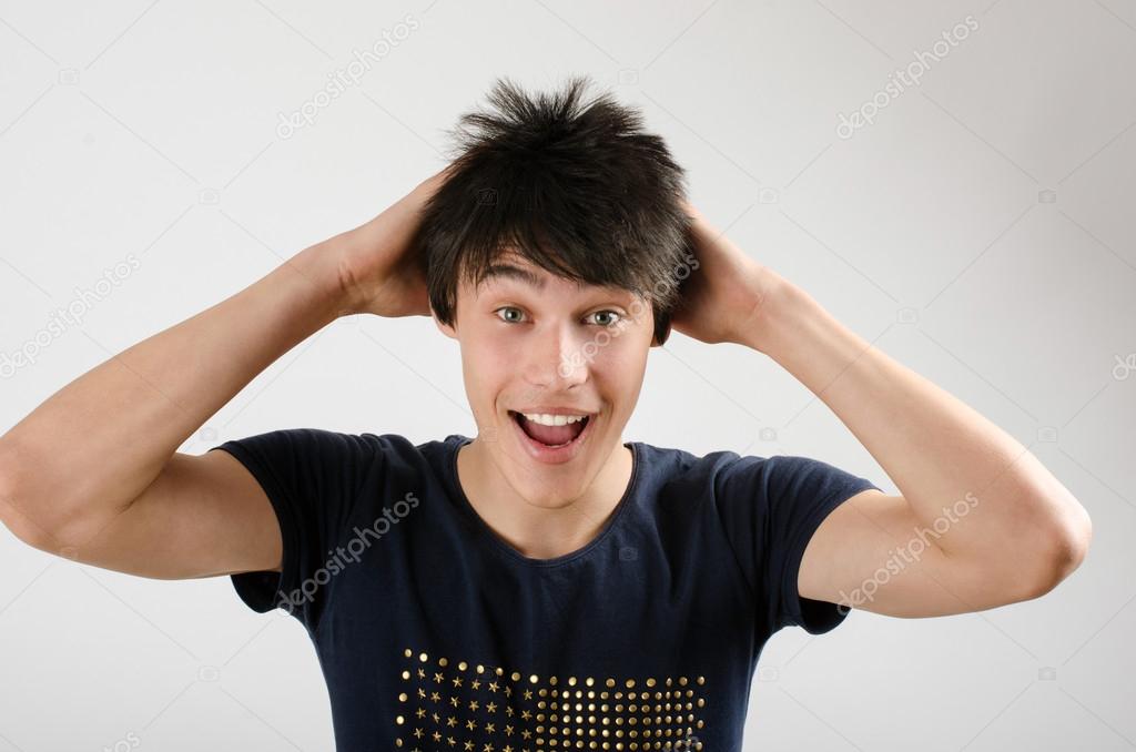 Young man with crazy hair holding his head screaming. Man being happy ...