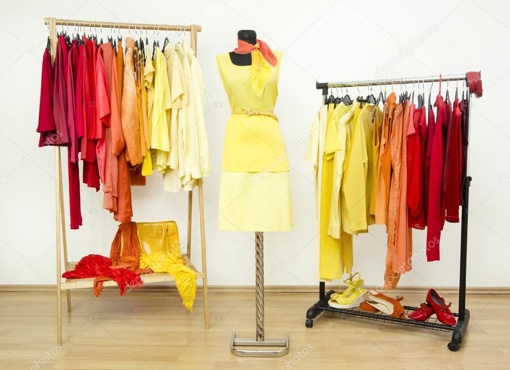 Wardrobe with yellow, orange and red clothes arranged on hangers and a ...