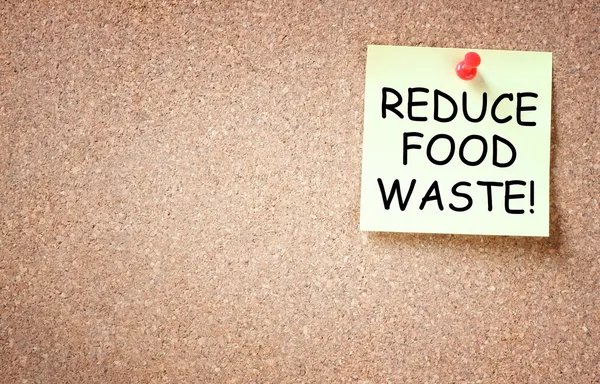 Sticky note pinned to corkboard with the phrase reduce food waste ...