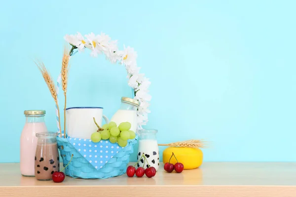 Photo of dairy products over wooden table. Symbols of jewish hol ...