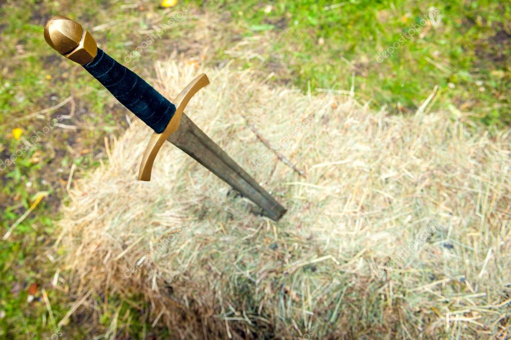 Medieval sword stuck in a pile of hay Stock Photo by ©klemsy 26531023