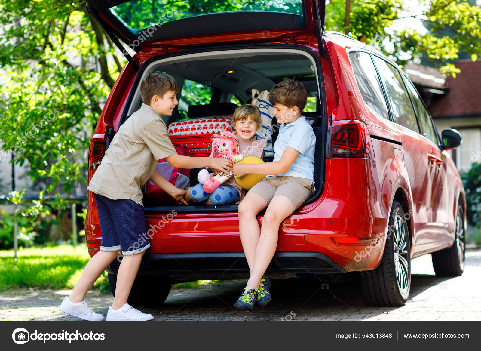 Three children, two boys and preschool girl sitting in car trunk before ...