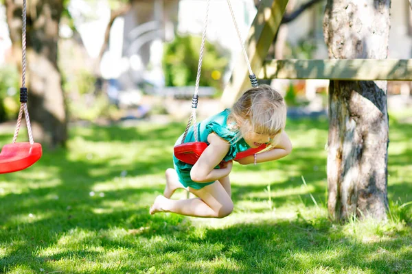 Little preschool girl jumping on trampoline. Happy funny toddler child having fun with outdoor ...