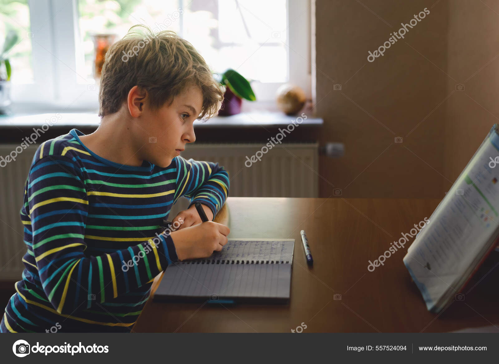 Hard-working school kid boy making homework during quarantine time from ...