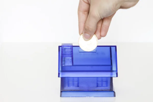 Blue House Money Box with man hand and coin on White Background Stock ...