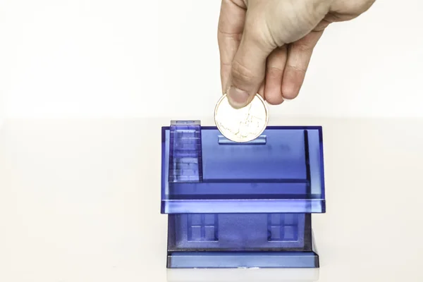 Blue House Money Box with man hand and coin on White Background Stock ...
