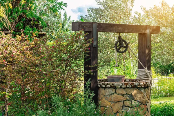 Beautiful artesian well made by stones and wheel pulley with metal ...