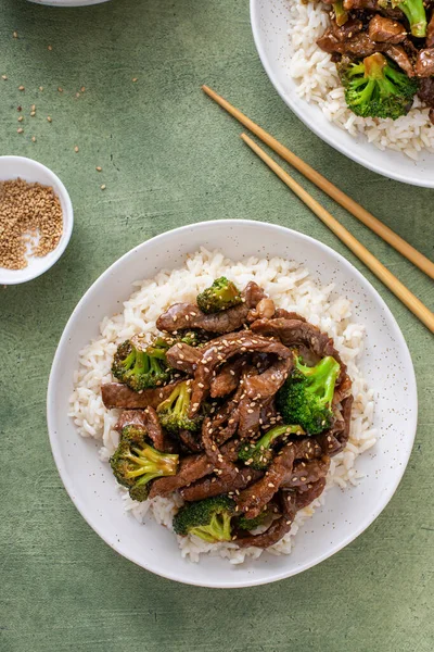 Beef and broccoli stir fry served over rice with sesame seeds top view ...