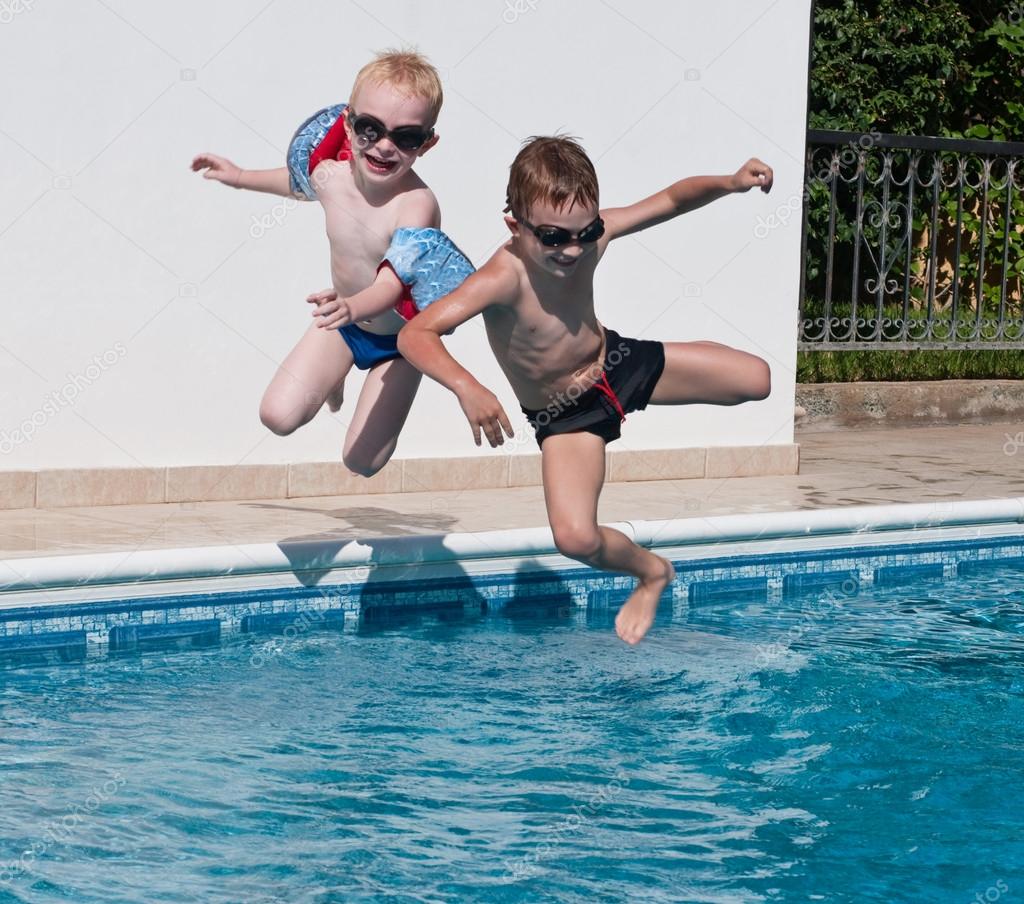Two boys jumping into swimming pool — Stock Photo © syaochka #12858418