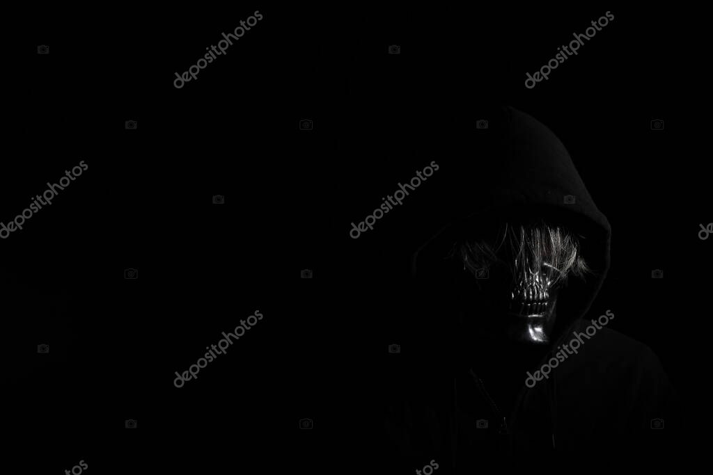 El hombre de horror con máscara de cráneo de pie en la oscuridad. 2022