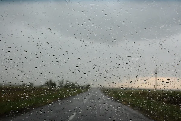 A rainbow is capture through a rain spotted windshield with the focus ...