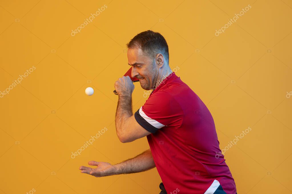 Man plays table tennis on yellow studio background. Professional player ...