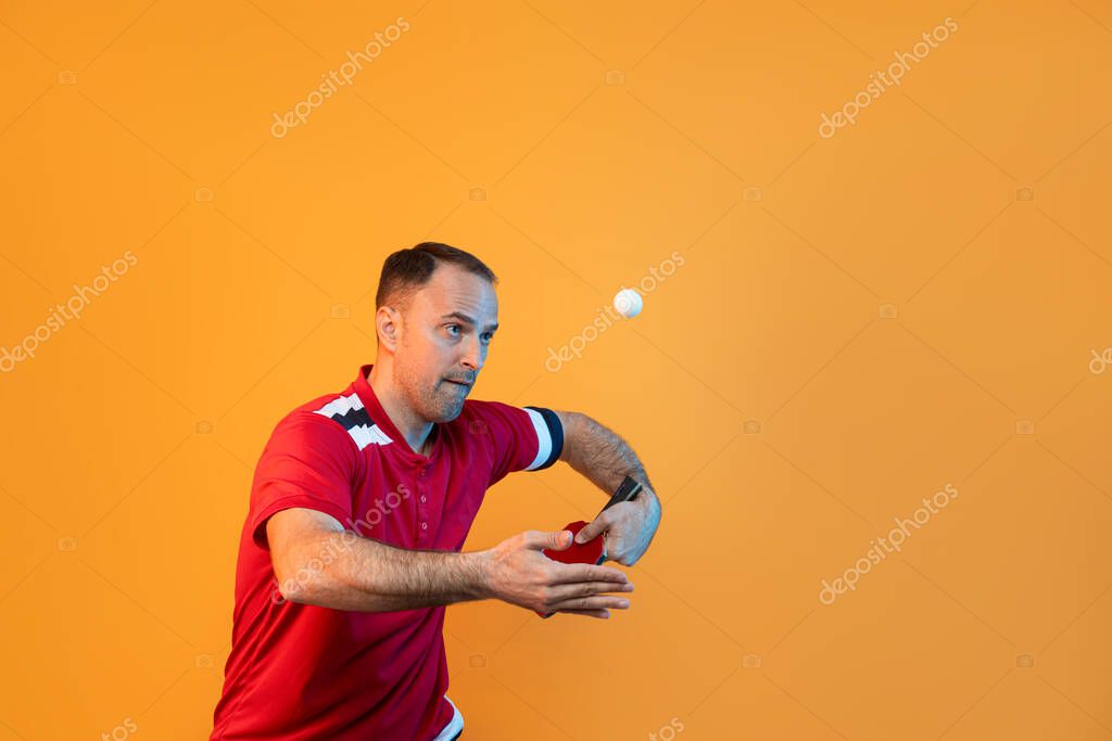 Man plays table tennis on yellow studio background. Professional player ...