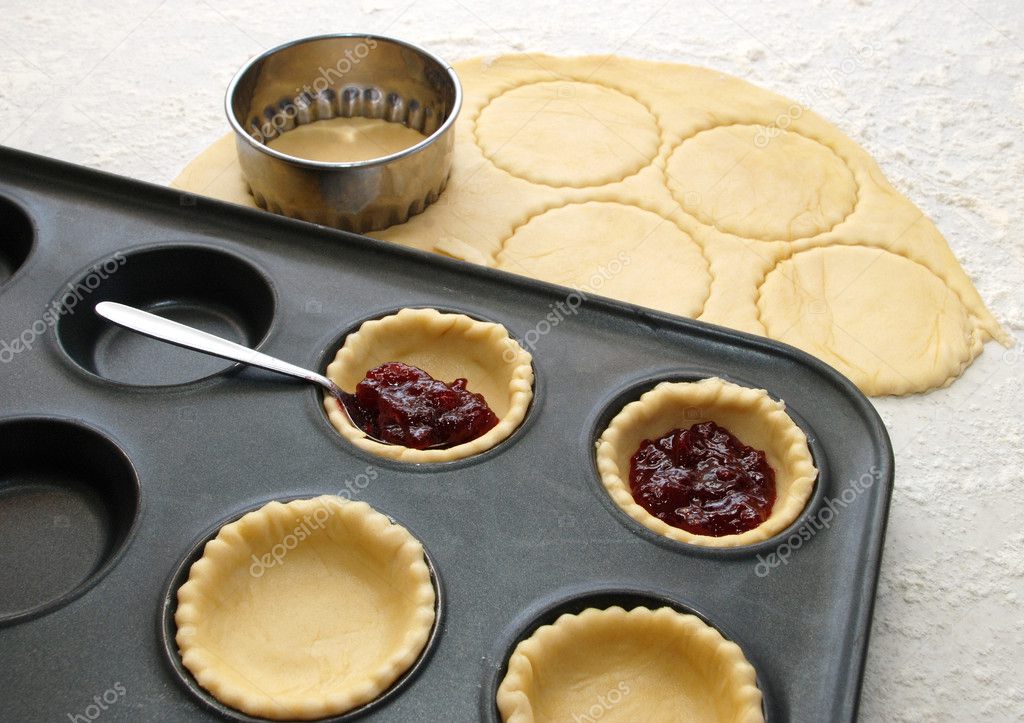 Cutting and filling pastry shapes to make jam tarts Stock Photo by ...