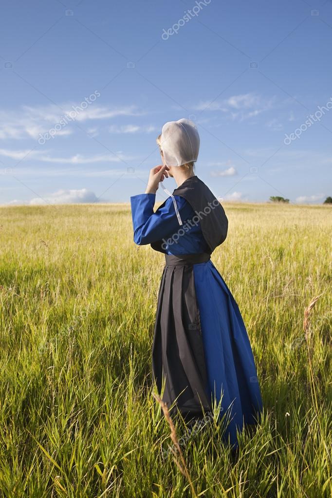 Amish woman standing in grassy field with afternoon sunlight — Stock ...