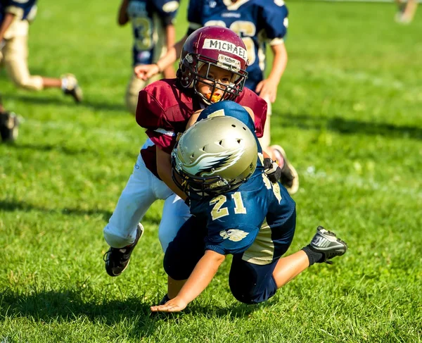 Youth football player tackles another - Stock Image - Everypixel