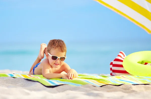 Cute kid sunbathing on colorful beach Stock Photo by ©olesiabilkei 31601475