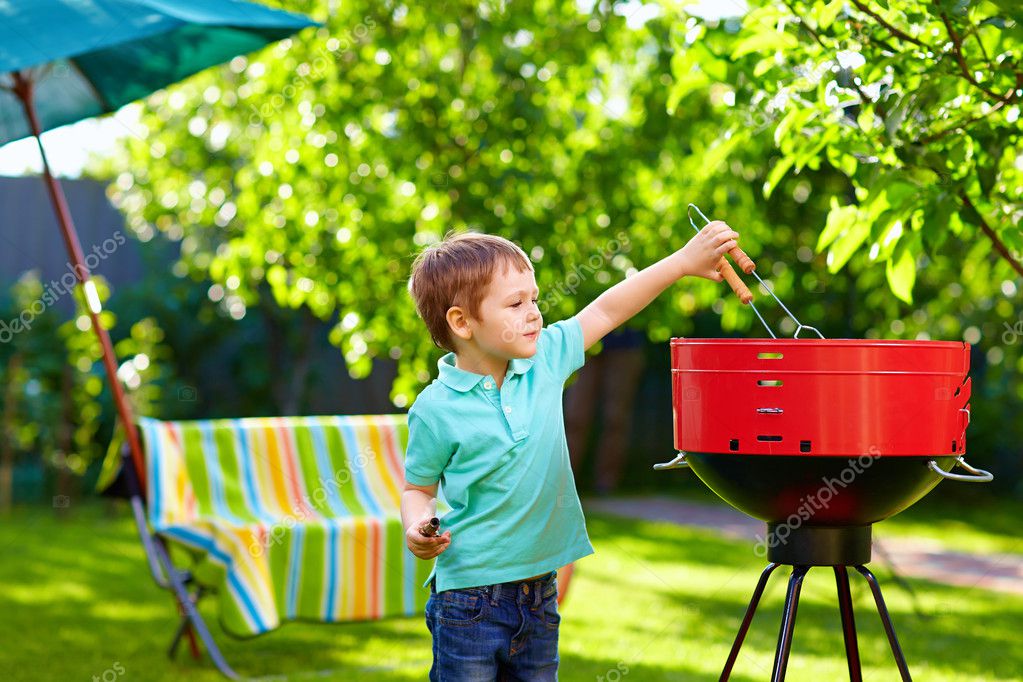 Kid grilling food on backyard party Stock Photo by ©olesiabilkei 46107683