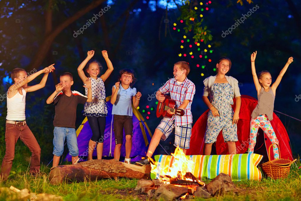 Happy kids dancing around campfire — Stock Photo © olesiabilkei #51543435